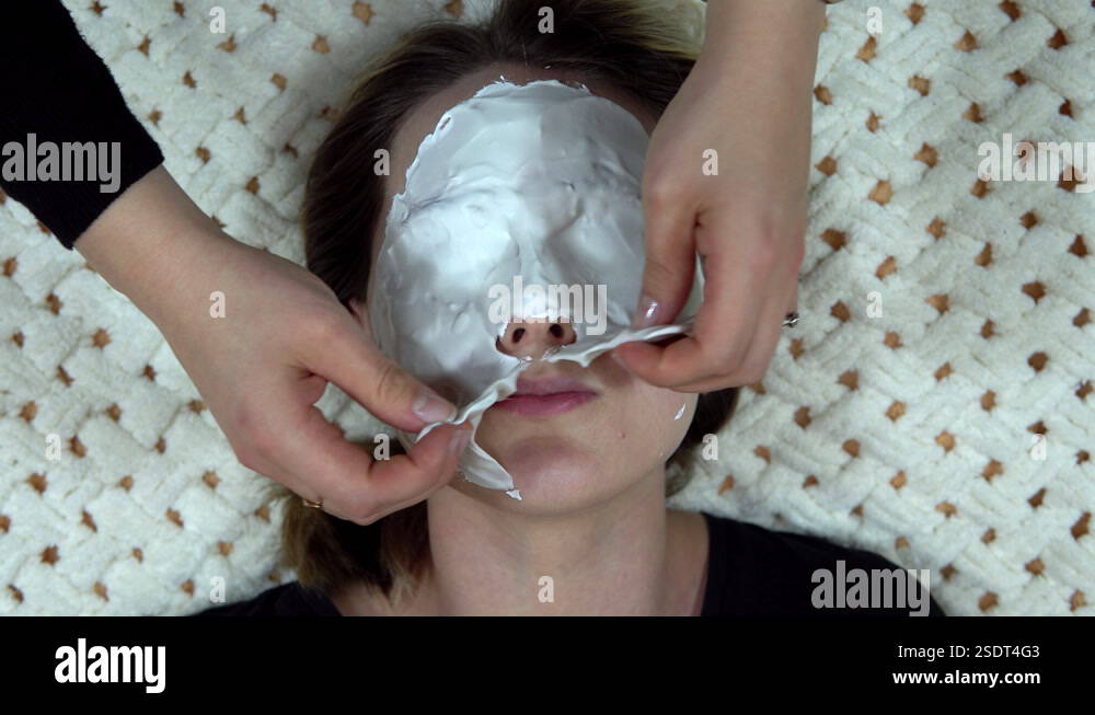 A white alginate face mask is removed for a woman to rejuvenate her ...