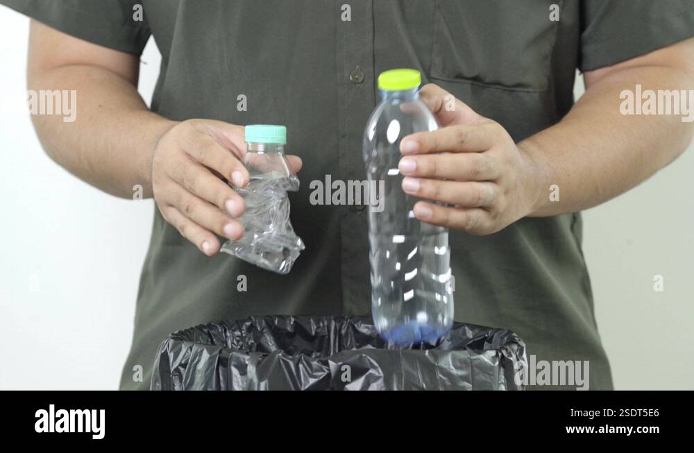Man holding plastic bottle and crumpled bottle dumping into the trash ...