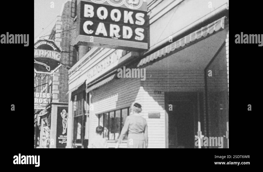 1950s: Woman and boy walk down street, look in store window, enter ...