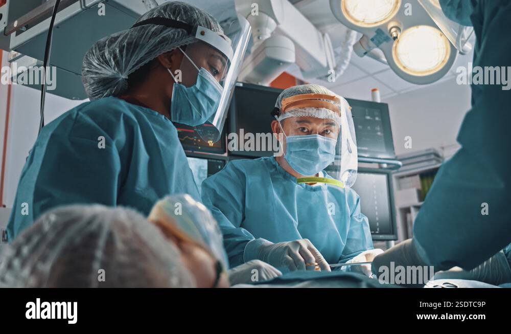 Low angle of the concentrated surgeon man with his assistants sutures ...