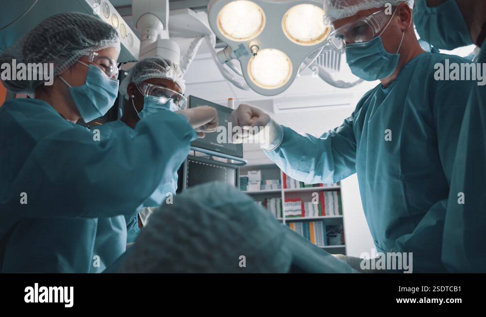 Chief surgeon and team bumping with fists after succeeding surgery ...