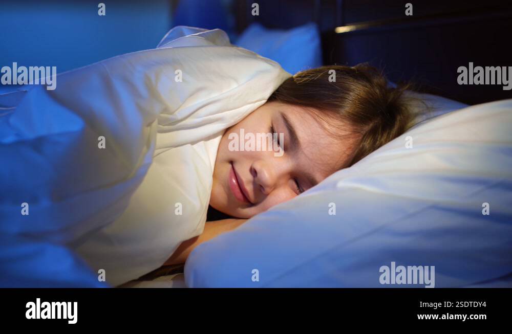 The girl naps in bed, sees a pleasant sleep, smiles, opens eyes and ...