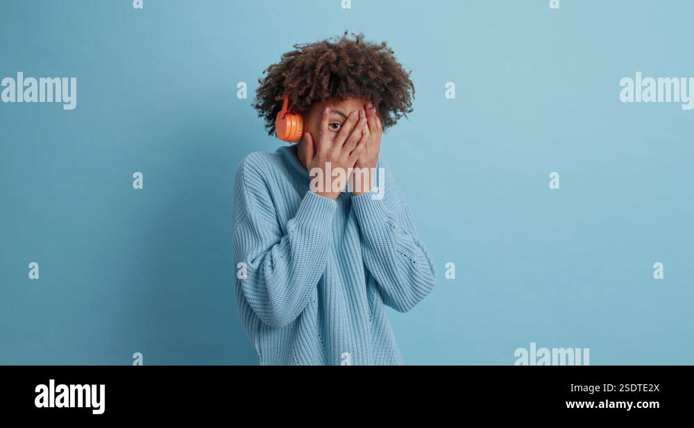 Scared curly haired woman afraids of something terrible covers face ...