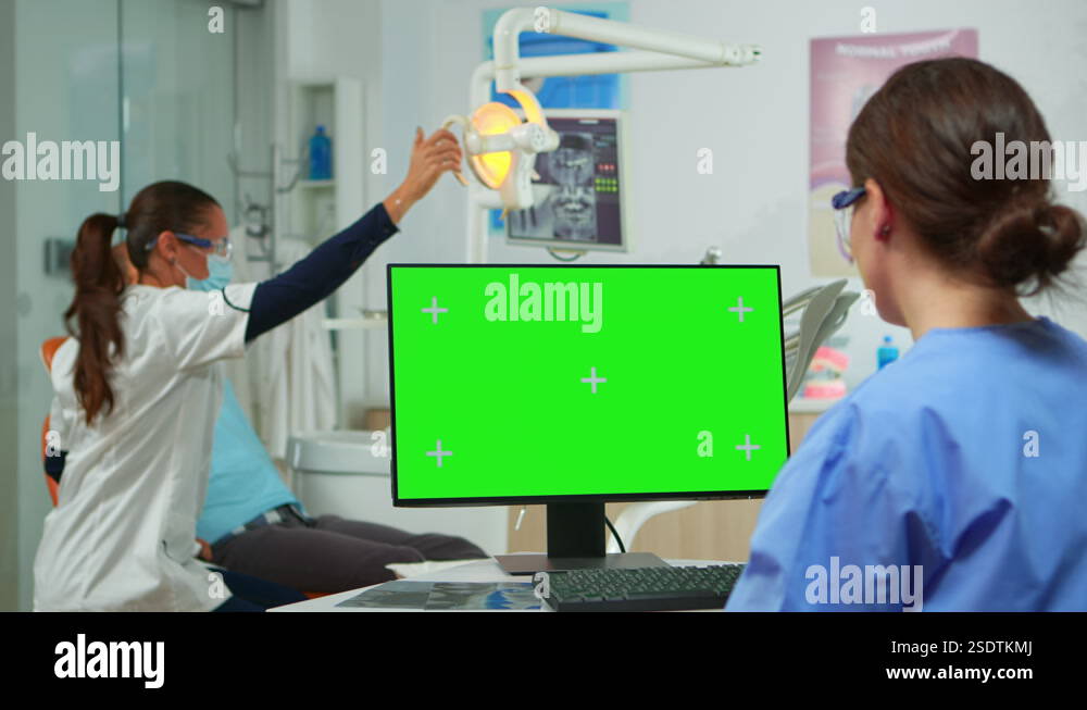 Nurse looking at green screen display while doctor examining patient ...