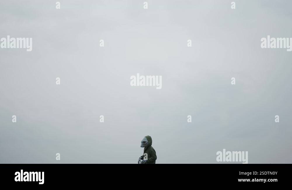alien in green suit stands alone in sky,alien arrived on earth rubbing ...