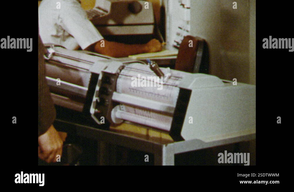 1960s: Needles record waves of information on readout sheet. Man looks ...