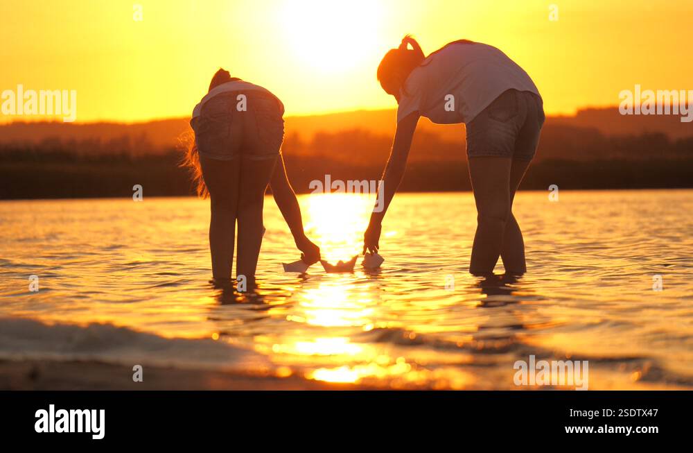 Children put a paper boat into water. Girls play with paper boats ...
