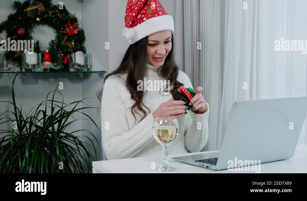 Portret woman is holding a gift and typing on a laptop during a video ...