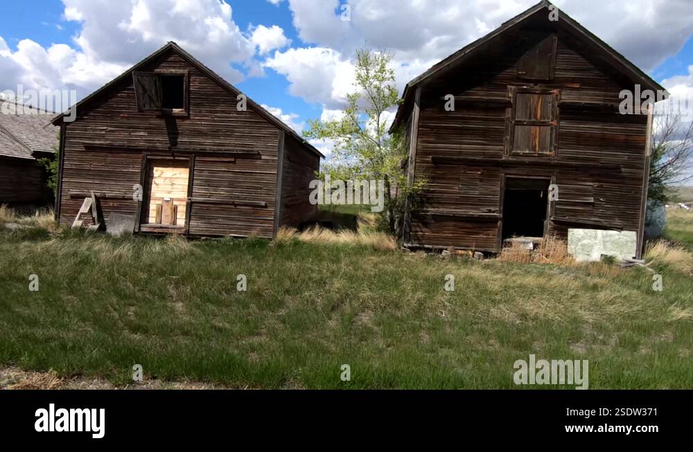 A old abandoned barns on farm land during a nice day with clouds in the ...