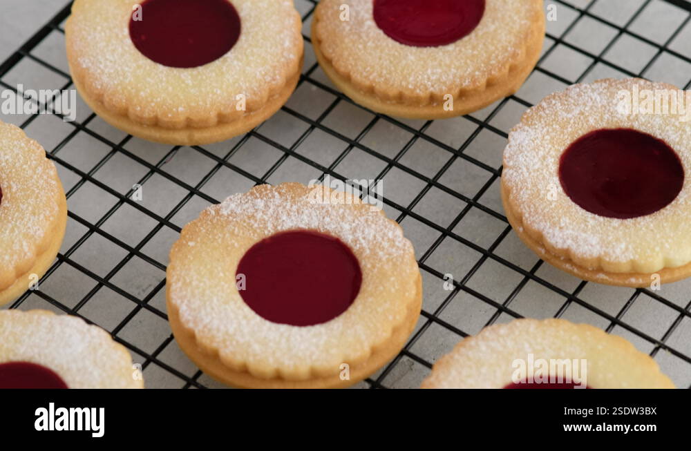 Jam cookies are on the wire rack. Female hands a making homemade ...