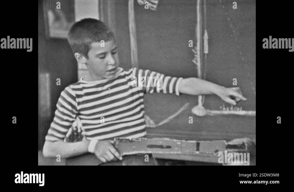 1960s: Boy holds paper gun, talks. Boy heats end of tube attached to ...
