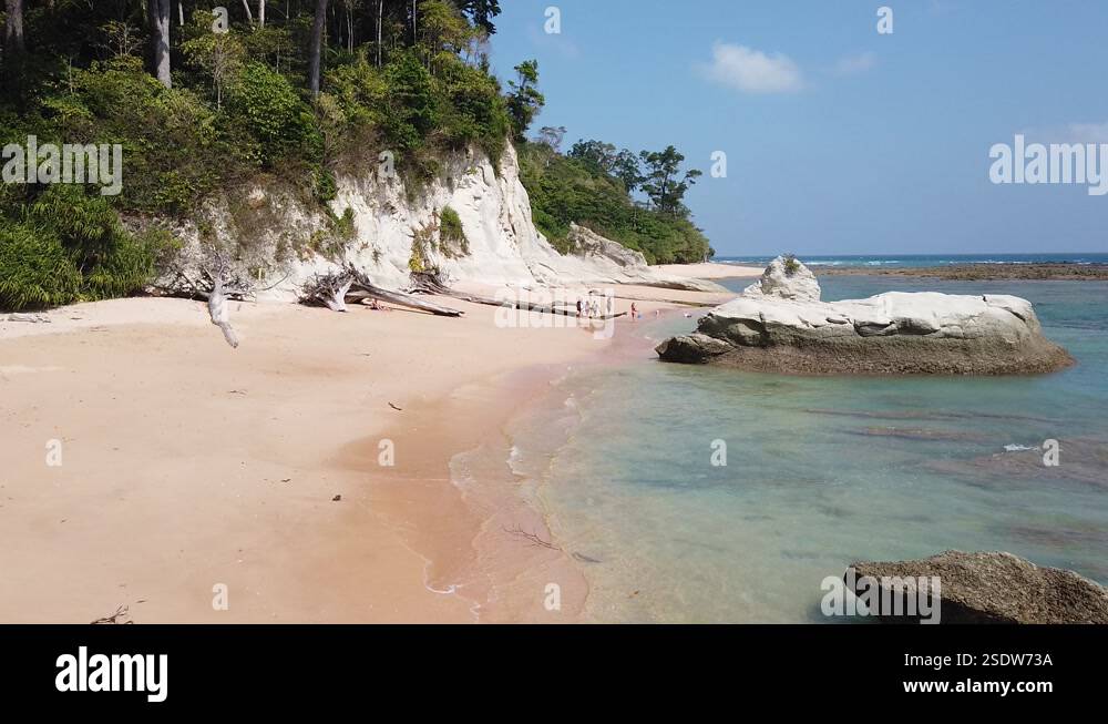A group of tourists explore a remote beach in the distance on a remote ...