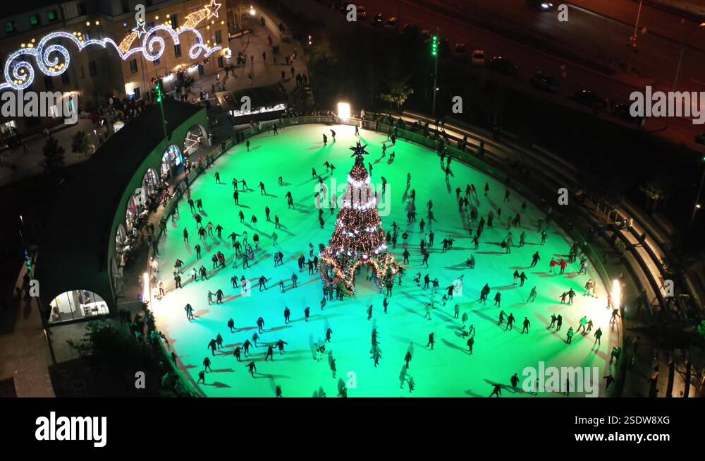 Ice skating rink with many people rolling and a Christmas tree in the ...