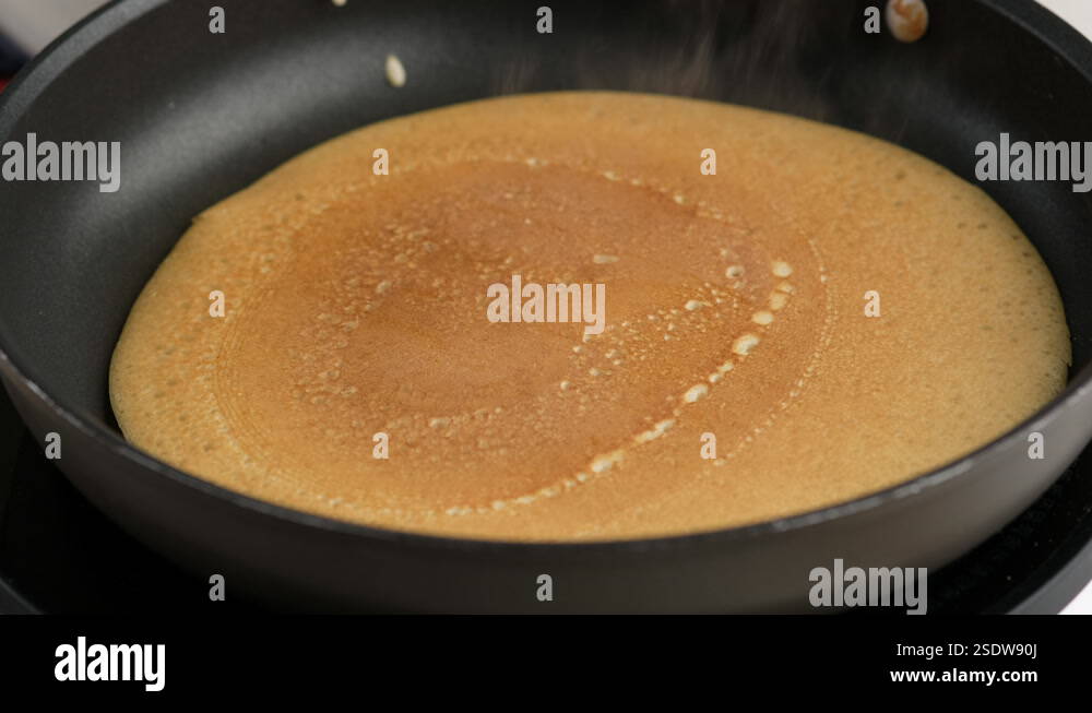 Turning a pancake in a pan. Big round pancake on induction frying pan. Cooking Stock Video ...