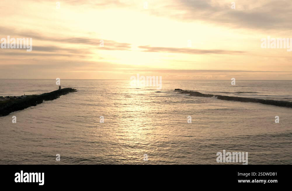 Drone flying between North and South jetty in Bandon Oregon at sunset ...