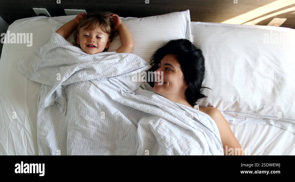 Cute baby and mother in bed blinking to camera. Top view Stock Video ...
