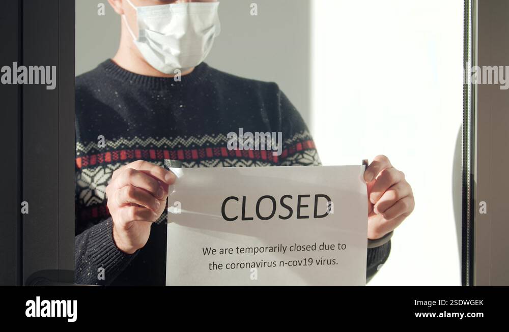 Male hanging a sign closed on the door. Portrait footage of man. Young ...