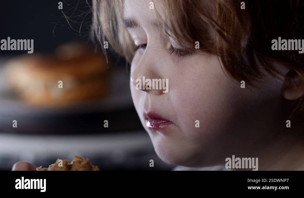 child is biting and chewing deep-fried chicken leg in fast food ...