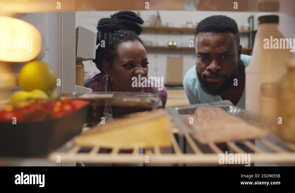 Afro-american couple opening fridge and wrinkling face having food ...