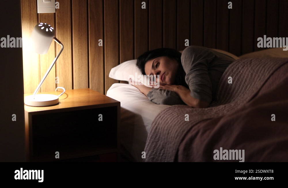 Woman lies in bed thinking before going to sleep. Person turning ...