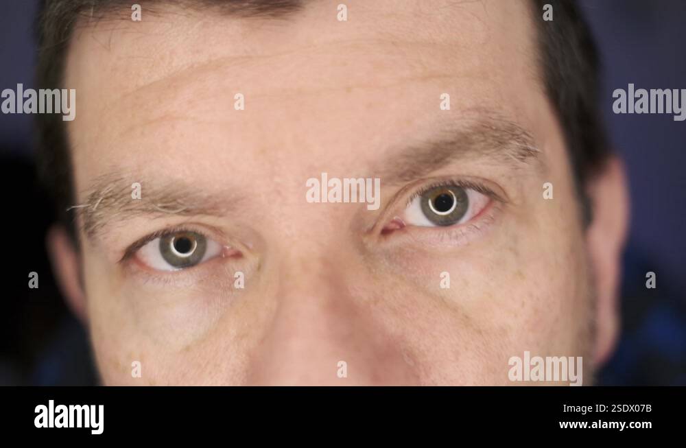 A man looking at the camera in an extreme close-up with eyes going in ...