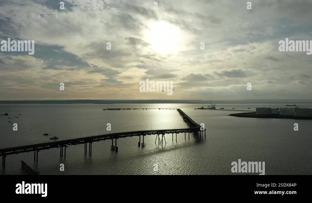 Aerial : flying away from the sun with pier walkway, industrial ...
