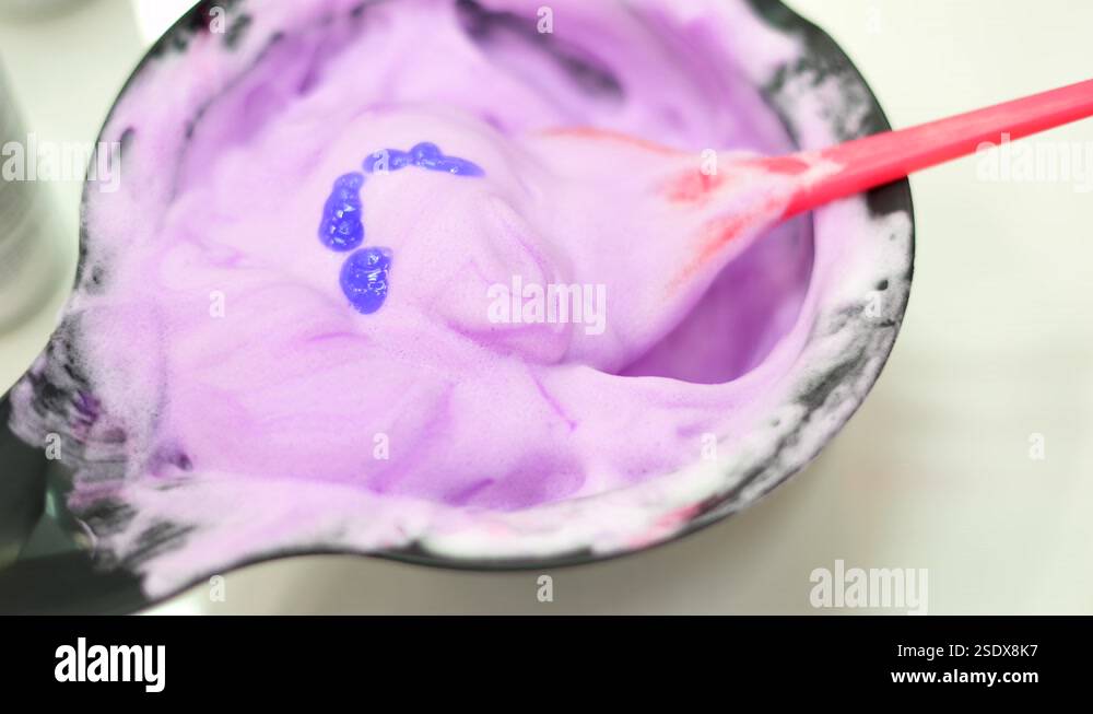 purple foam for dyeing in blond with blue drops of pigment in a plastic ...