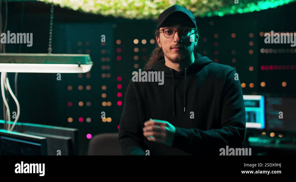 Portrait of a young male hacker looking at the camera in a secret ...