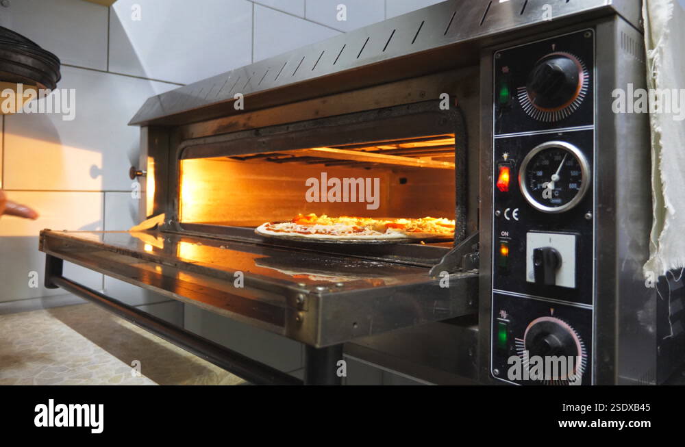 Male hand of cook opening the oven and putting uncooked dish at cuisine ...