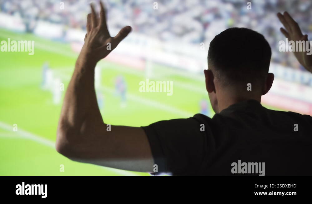 A man cheerleader is watching a sports match on the background of the ...