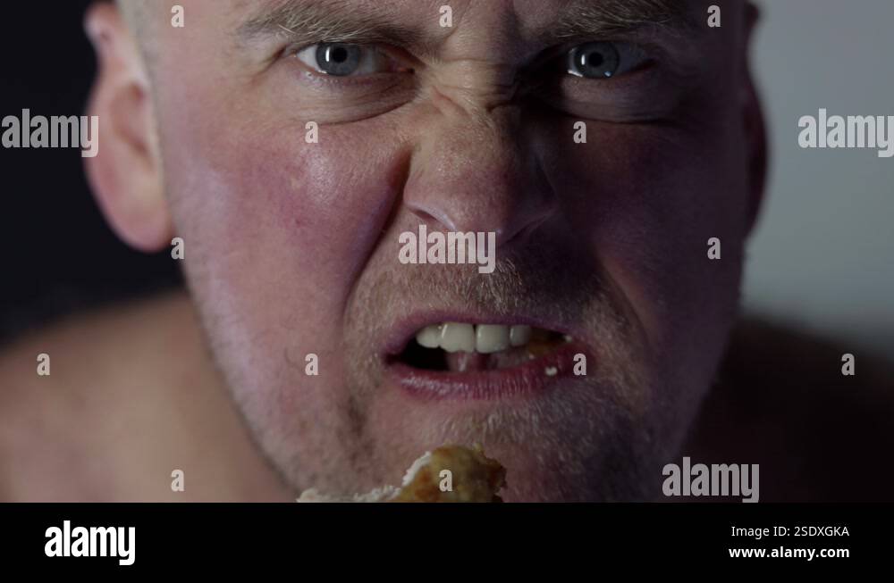 Hungry, angry and angry man eating fried chicken leg in breadcrumbs ...
