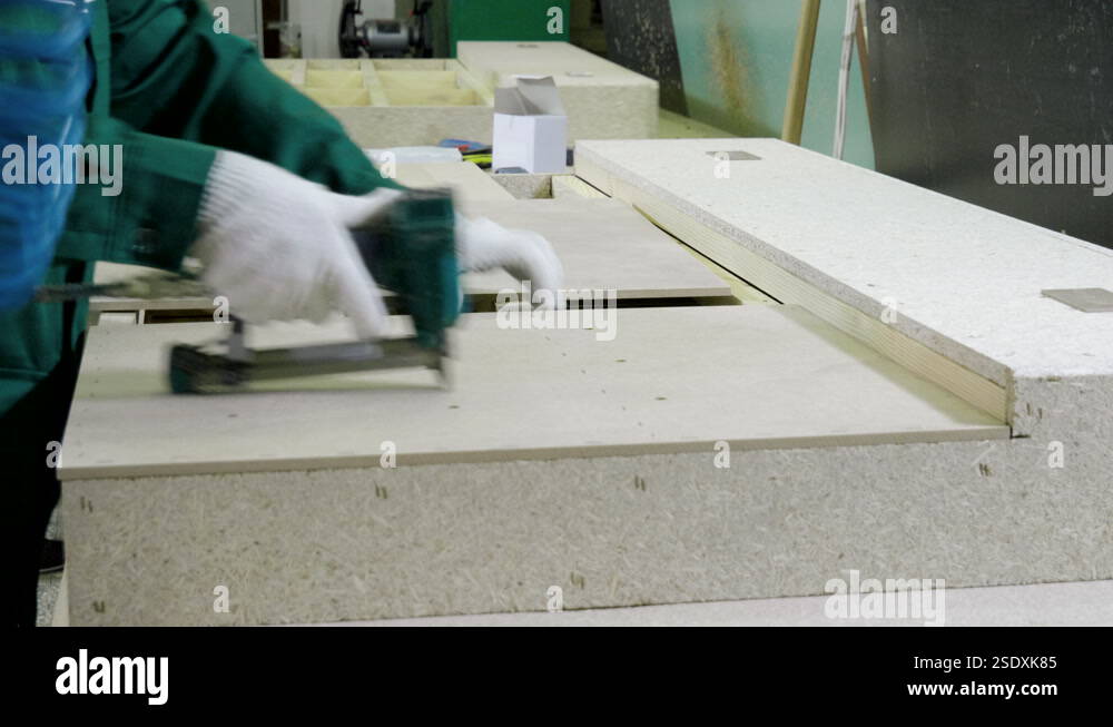 Workers dressed in uniform make a sofa, couch, settee in a furniture ...