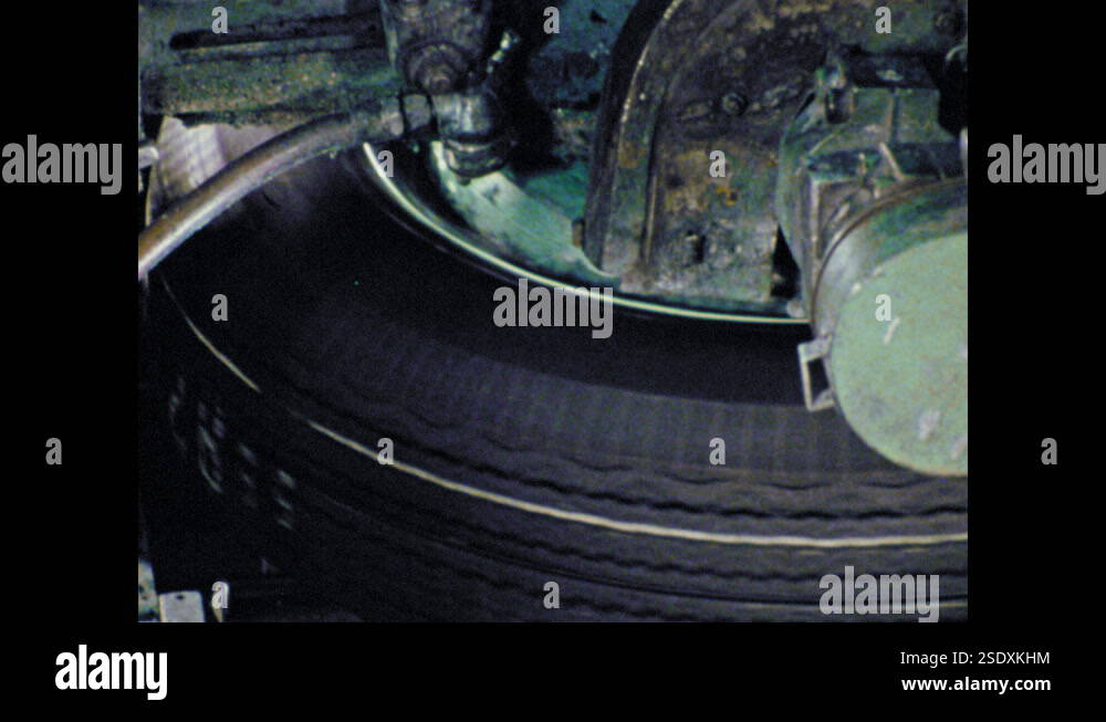 1970s: Conveyor belt of completed tires roll by. Tire is balanced by ...