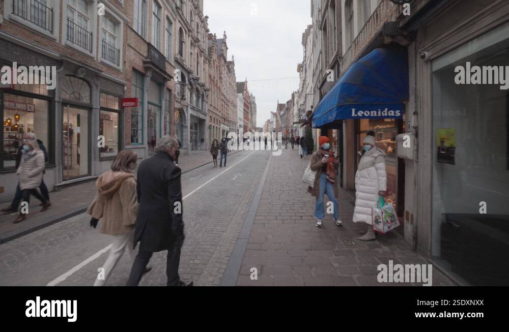 Crowd of masked people walking in shopping street Steenstraat in Bruges ...