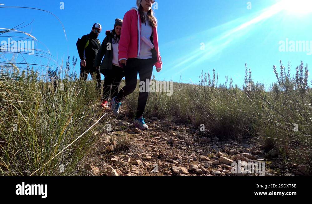 Hiking group walking through path in mountain top against beautiful ...