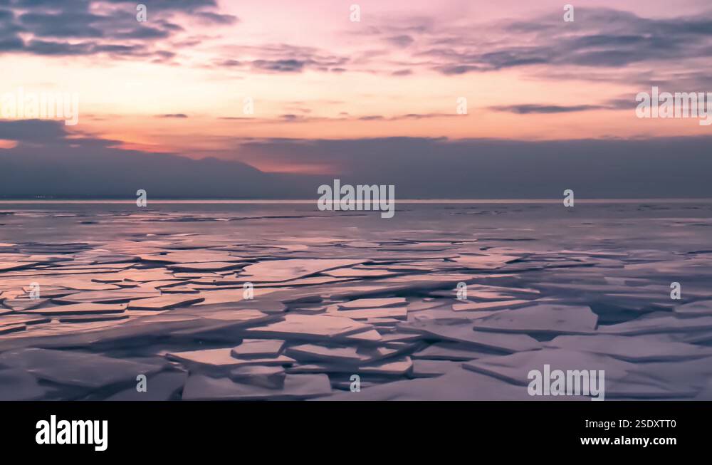 Rafted ice frozen in place on a lake, sunrise, mountains, cloudscape ...