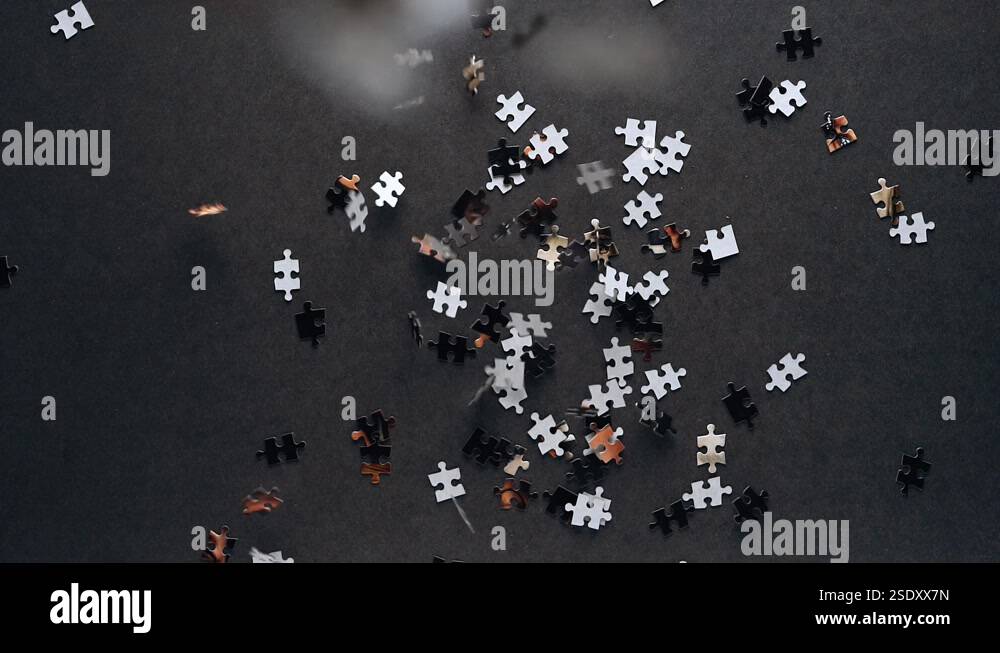 Jigsaw puzzle pieces falling down in slow motion onto gray table top ...