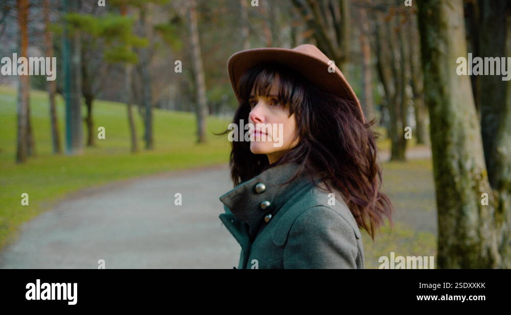 Young woman turns around to look behind and smile to somebody off ...