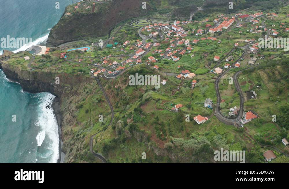 Traditional red roof houses on steep green slope of volcanic Madeira ...