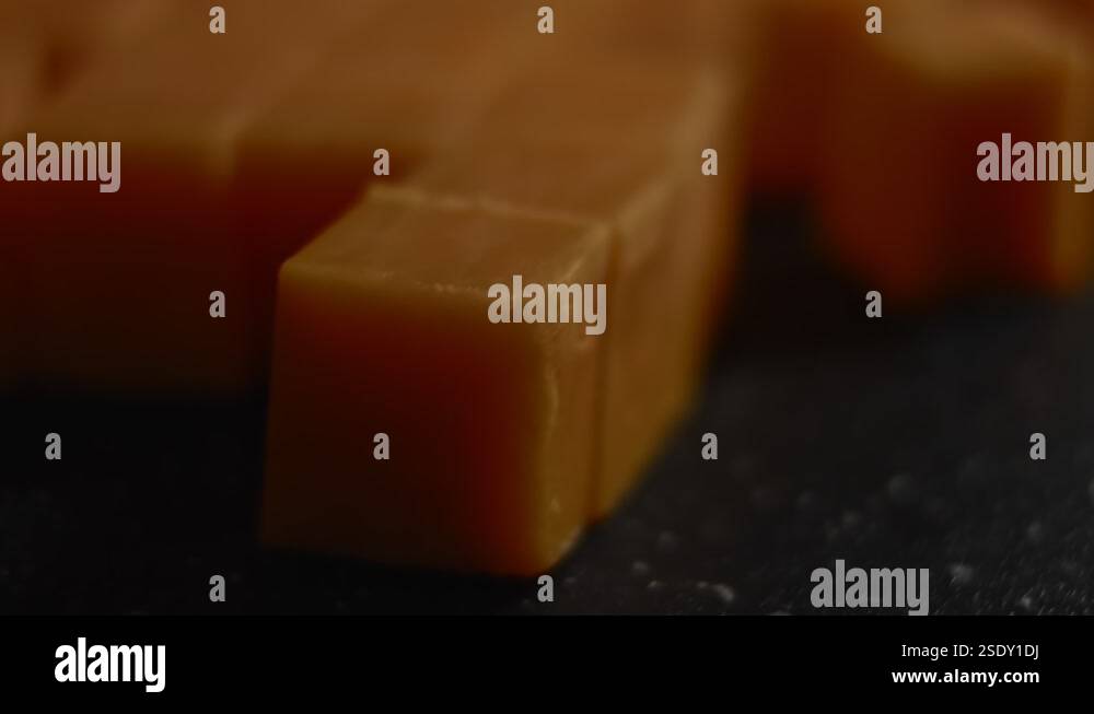 Cheddar cheese block cut on a cutting board. Cubed cheddar cheese as ...