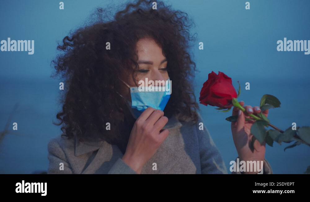 Close-up girl takes off the medical mask and sniffs the rose. She doesn ...