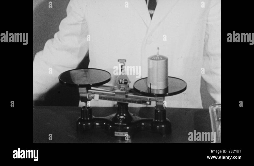 1960s: Man in lab places weight on scale. Man places weight in cup of ...