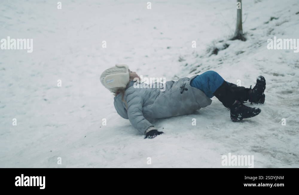 Girl rolls down snowy hill after struggling to slide on back, Slow ...
