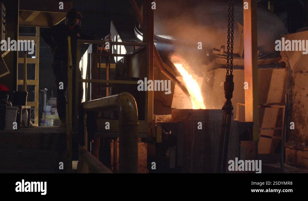 Man pouring hot lava into a mold in a refractory mold in the ...