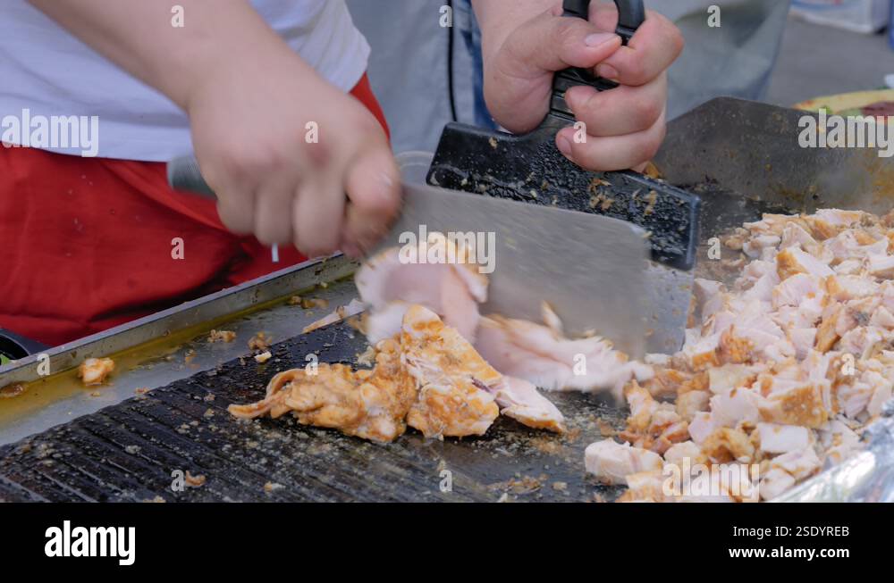 Slow motion: chef cutting chicken meat on grill at street food festival ...