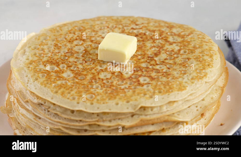 A lump of butter melts on a stack of hot pancakes. Camera movement. Big ...
