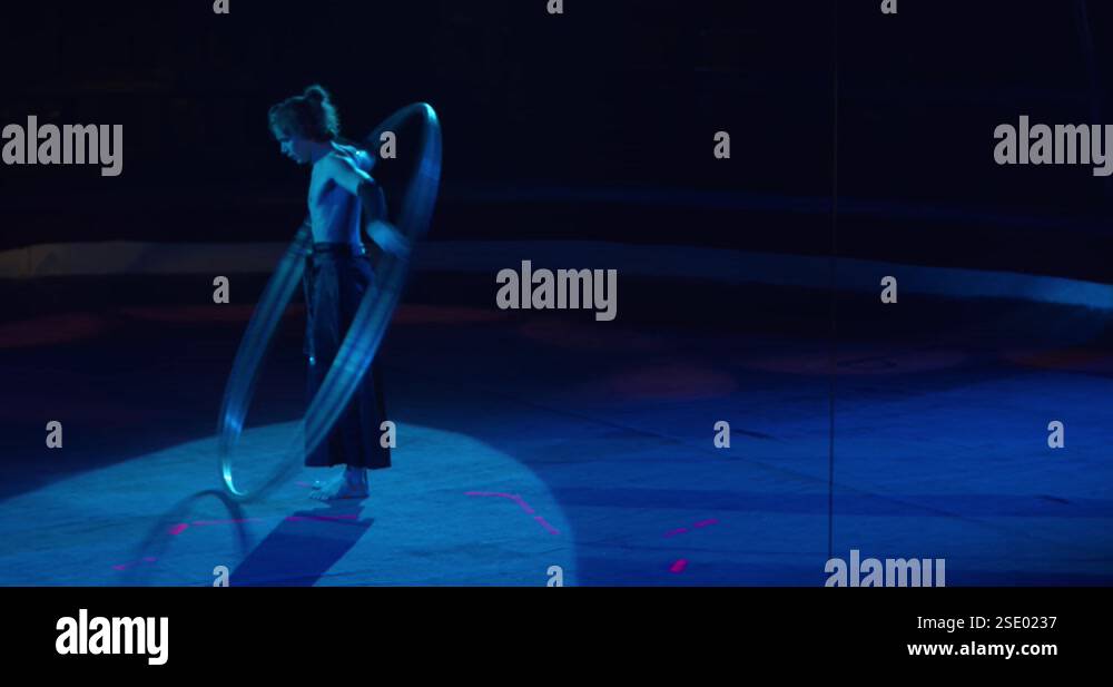 Circus performer is standing on stage under the spotlight, spinning the ...