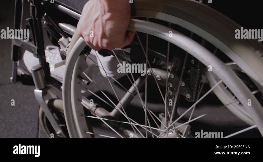 Close-up hand controls wheel of wheelchair. Hand pushing wheel of ...