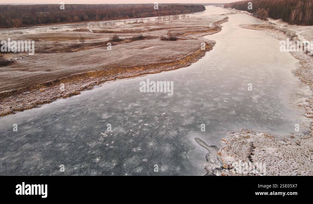 Aerial view of a snow-covered field at the edge of a frozen reservoir ...