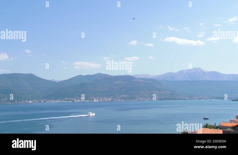 Yacht crosses Boka Kotorska Bay in Adriatic sea. Tourist plane flies ...